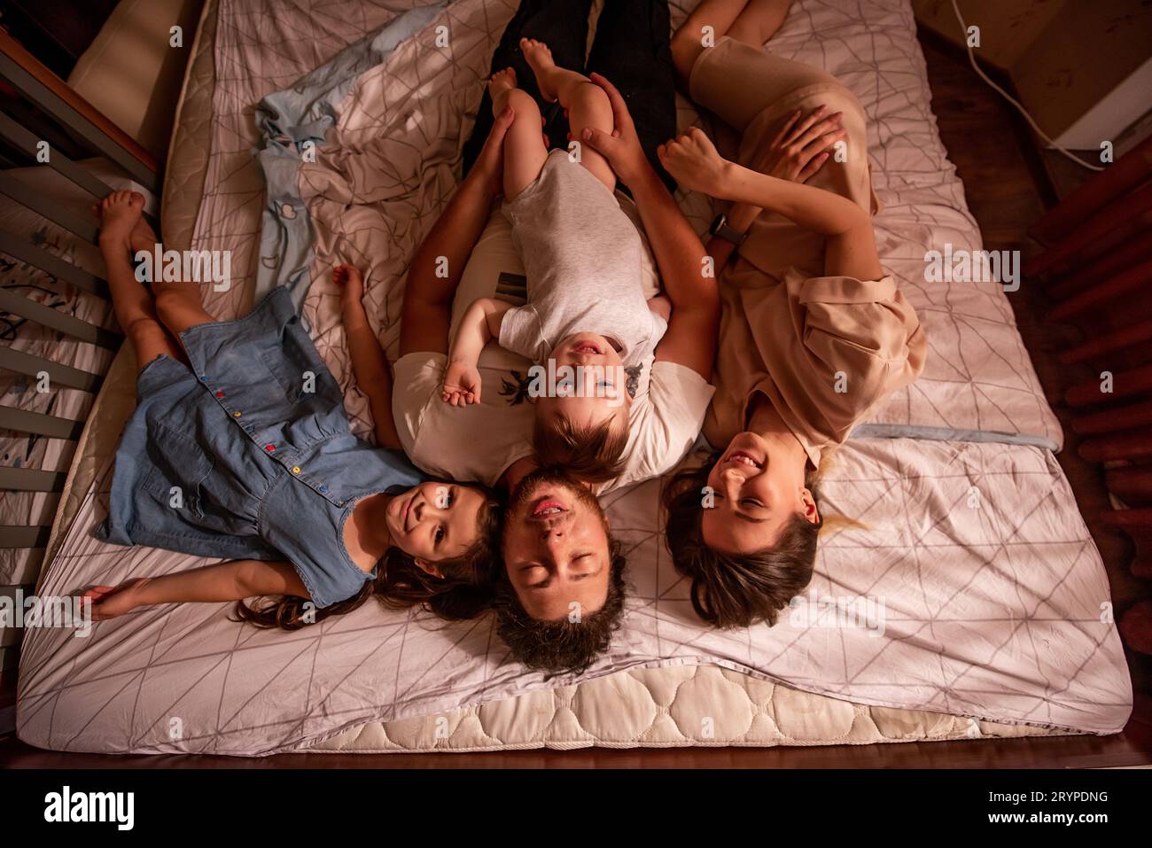 Top view of a cheerful family lying on the bed in the morning. Stylish ...