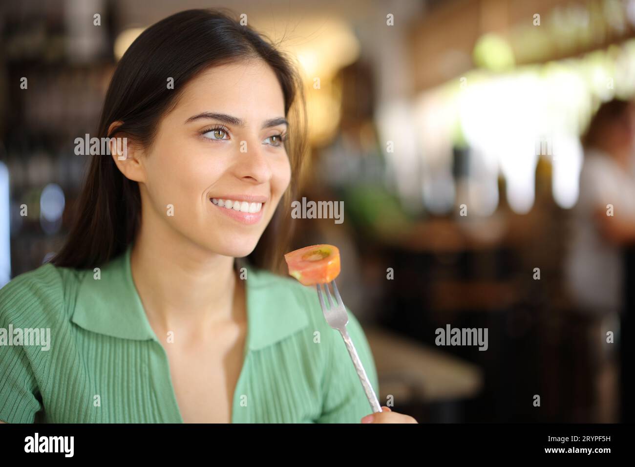Happy customer eating tomato in a restaurant interior Stock Photo - Alamy