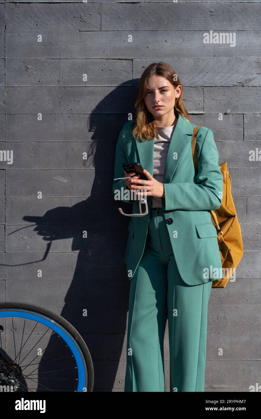 Stylish business ginger-haired woman in green suit and yellow backpack ...