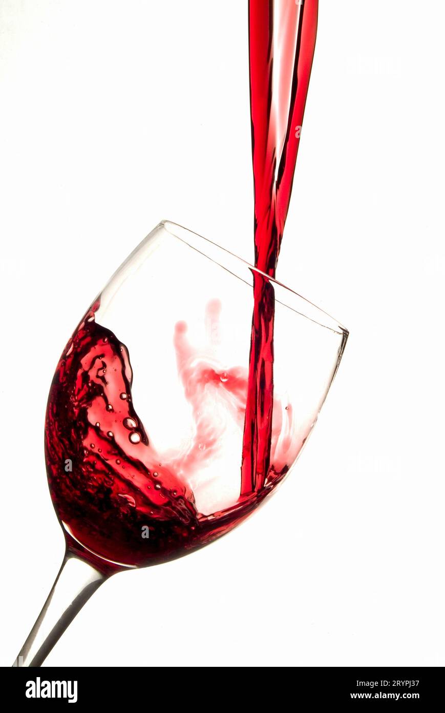 Red wine splashing into a tilted wine glass Stock Photo - Alamy