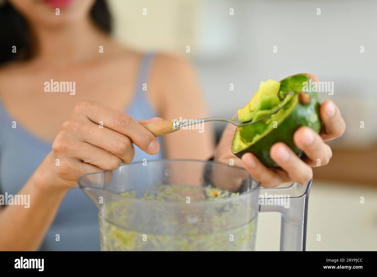 Closeup woman putting avocado into blender to making healthy smoothie ...