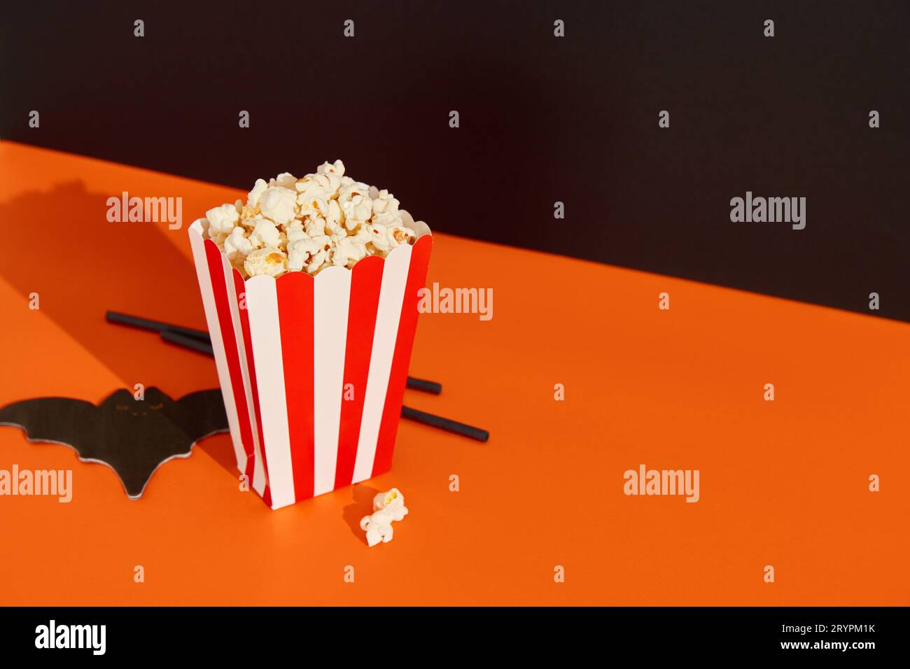 Striped box with popcorn, bat napkin and straws on an orange black ...