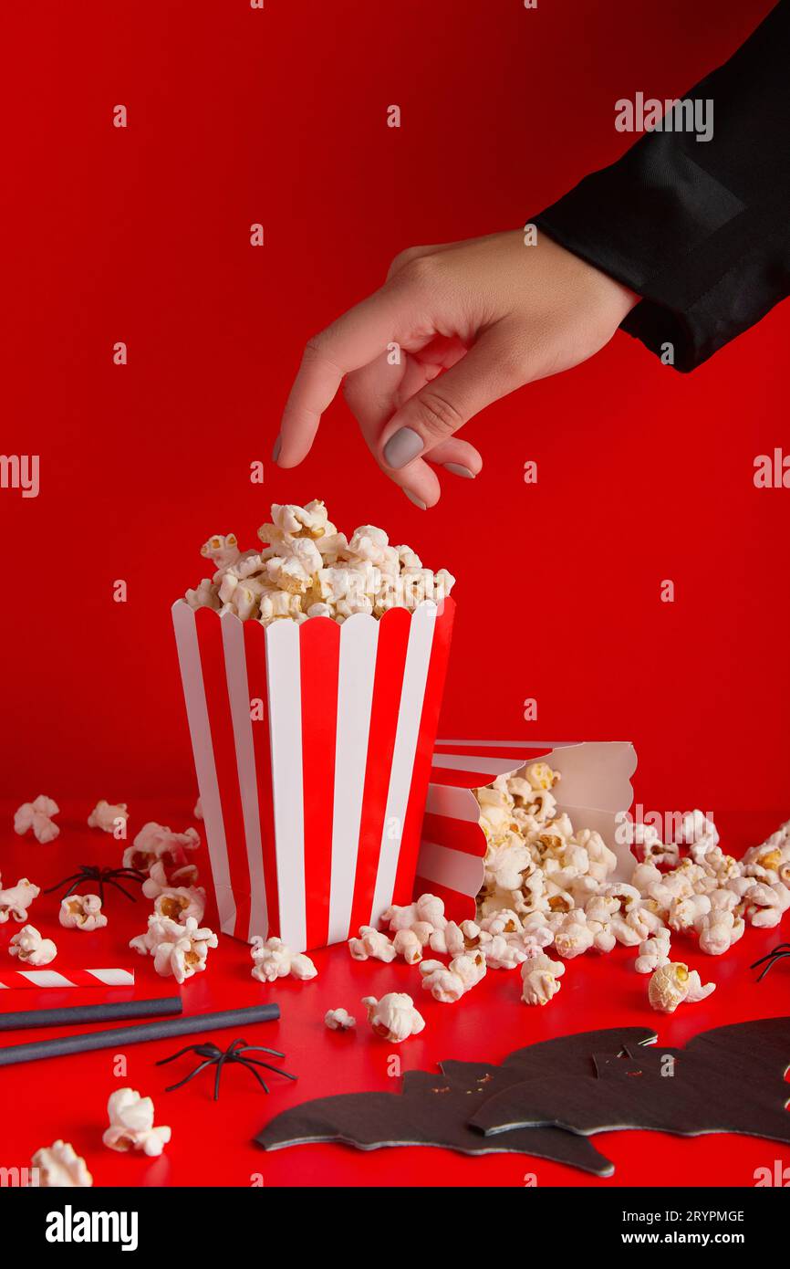 Womans hand taking popcorn from striped box, bat napkin and straws on a ...