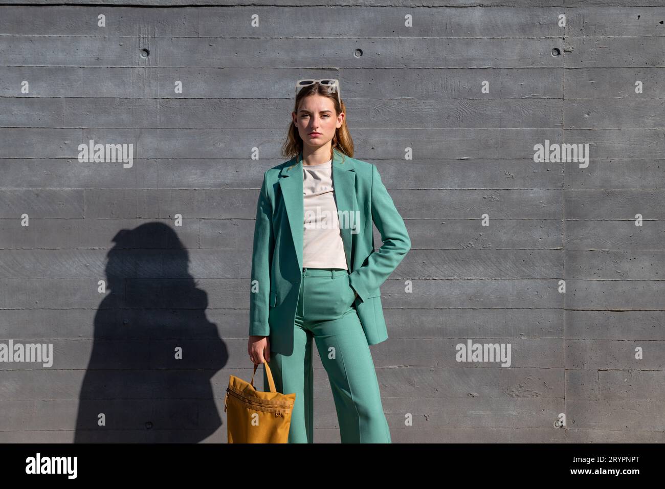 Young empowered ginger-haired woman in green suit, white sunglasses and ...