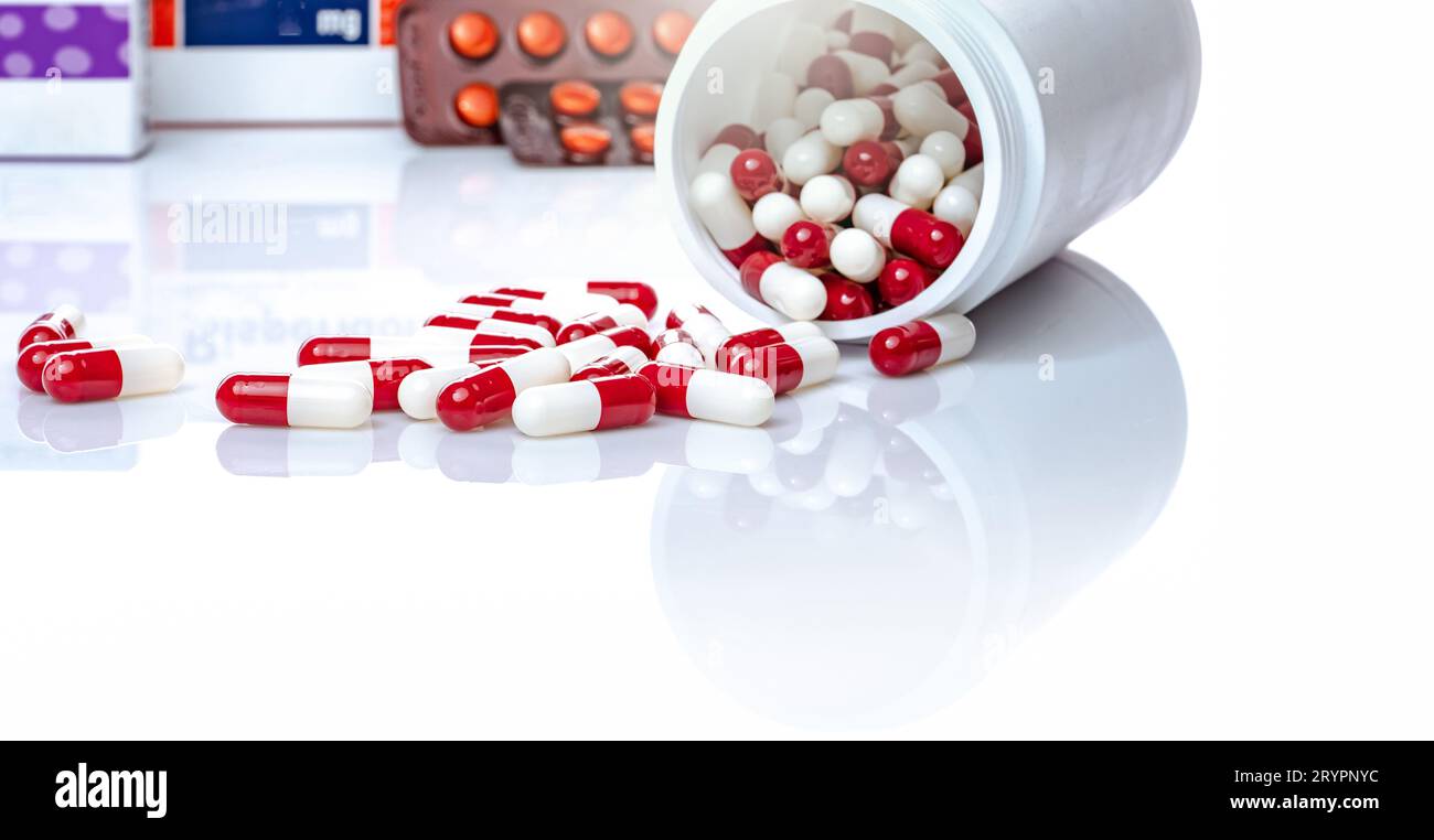 Red and white capsules pill spilled out from white plastic bottle ...