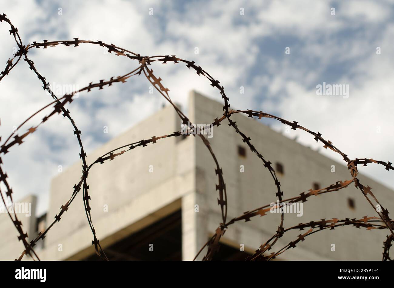 Rusty barbed wire fence against the backdrop of an abandoned bui Stock ...
