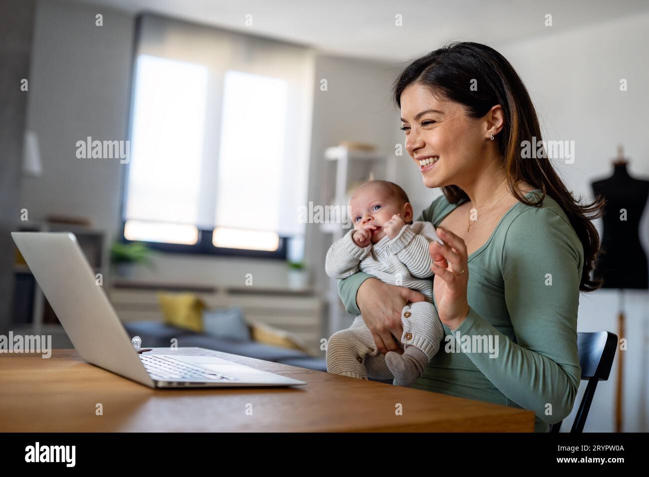 Mother with baby having video call online, conversation with relatives ...