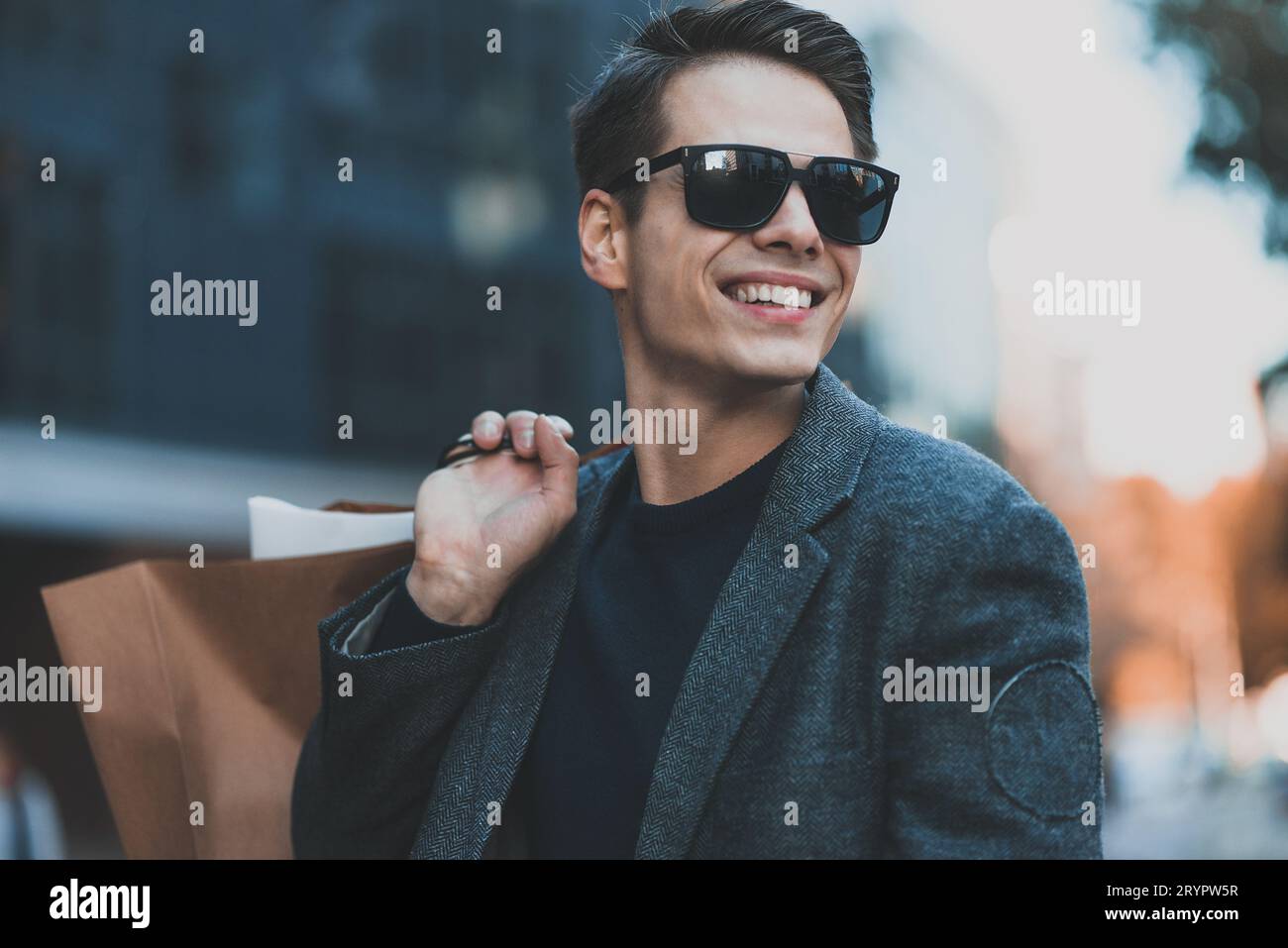 Happy stylish young man walking in urban street and enjoying Black ...