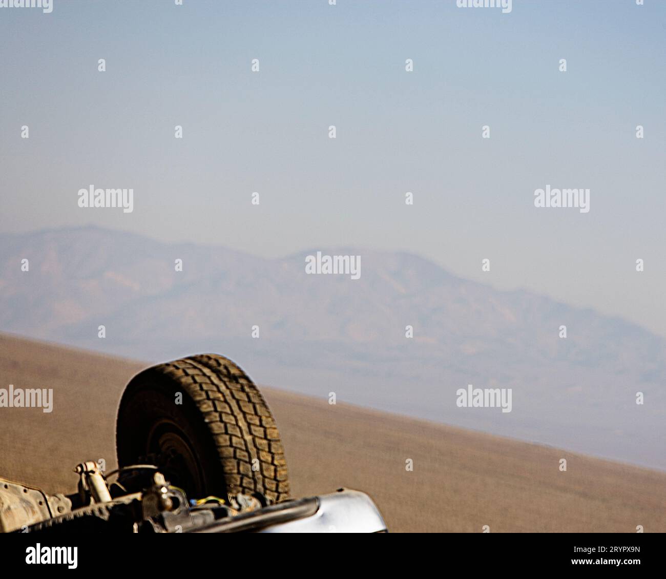 The rear wheel of a upside down auto in the desert. Photo manipulated ...