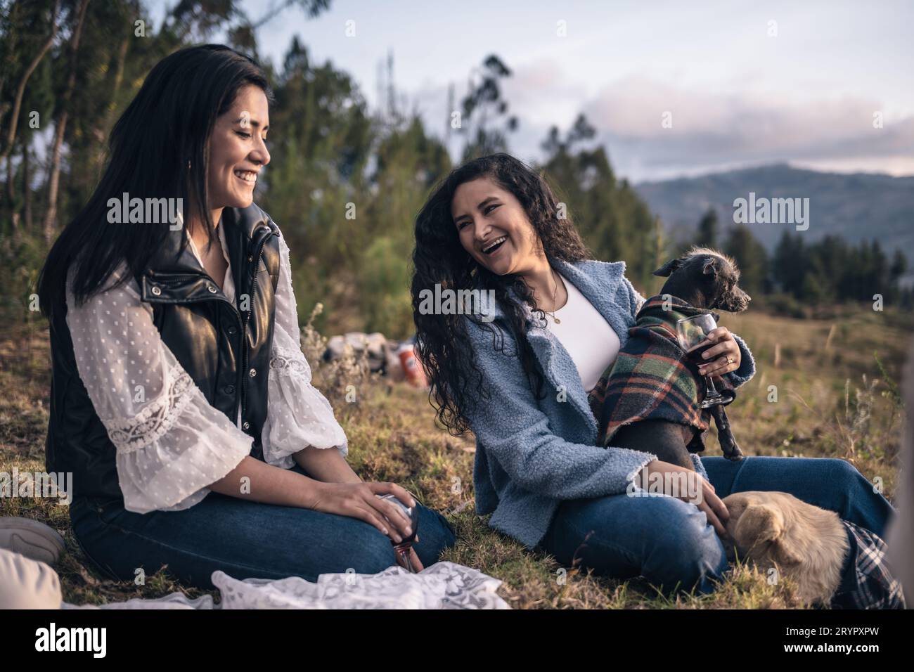 Women female friends smile and their dogs enjoy a picnic in nature ...