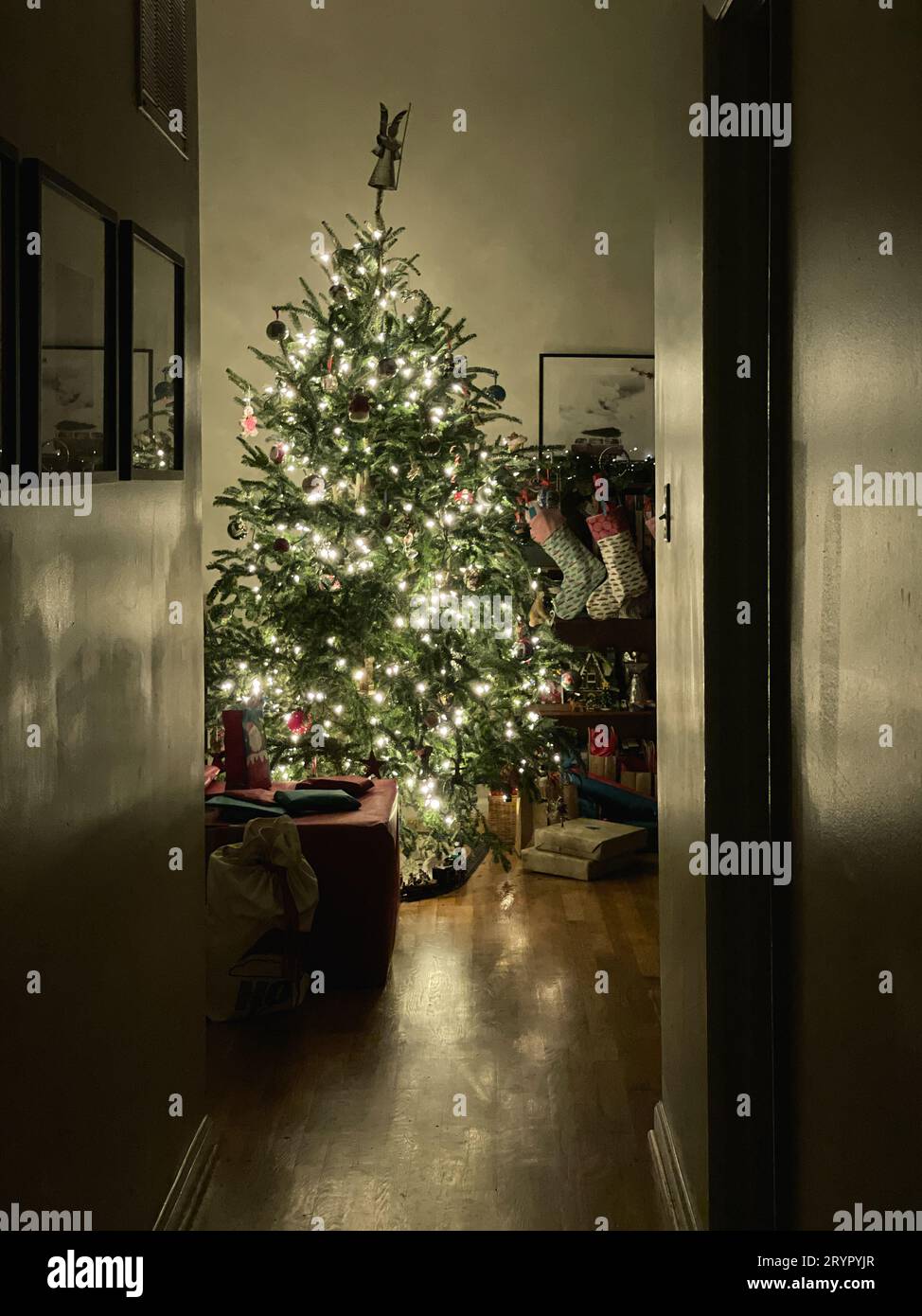 Vertical view of presents underneath a lit Christmas tree Stock Photo ...