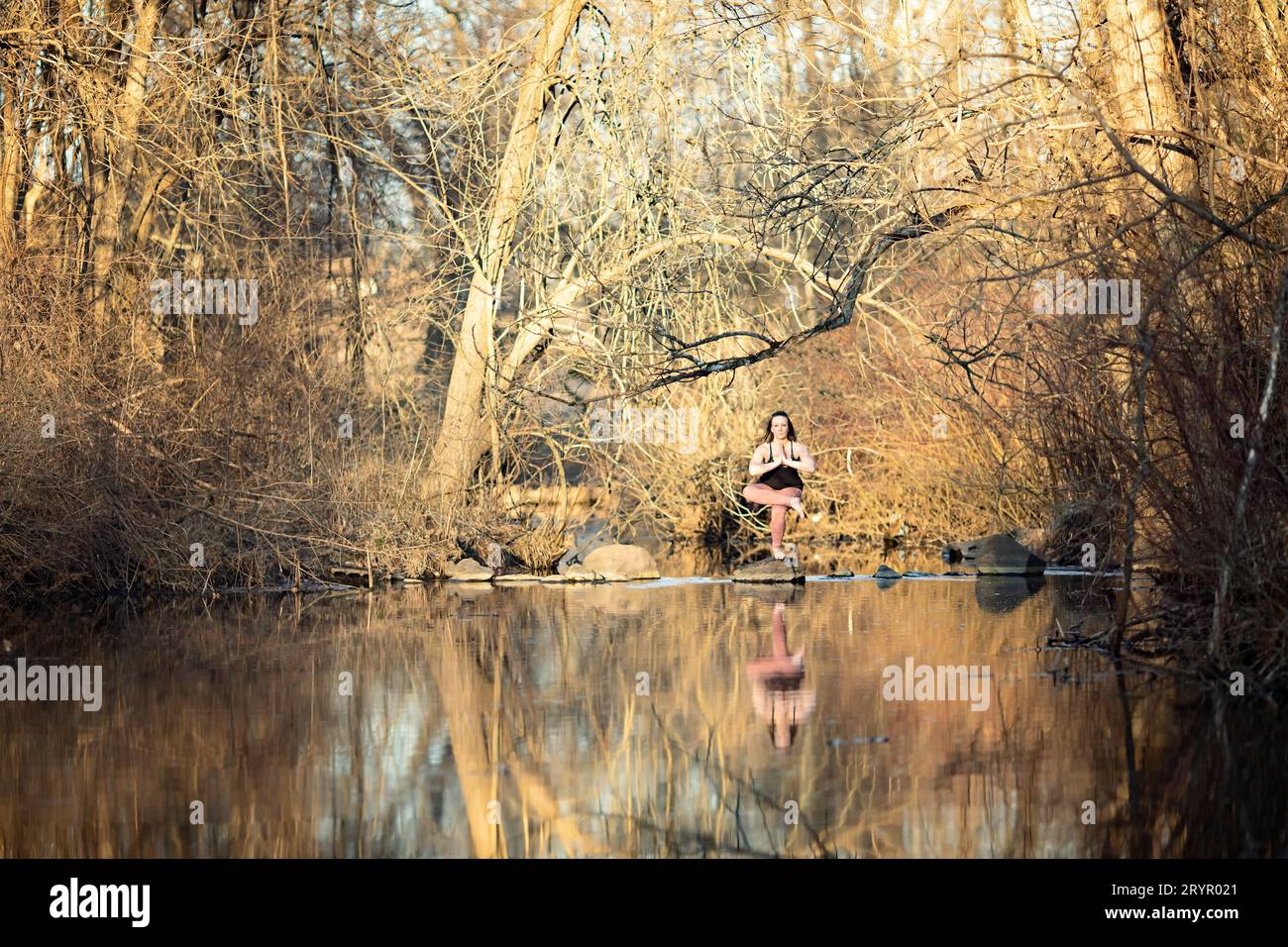 Woman practicing yoga outdoors by a pond; water reflection Stock Photo ...