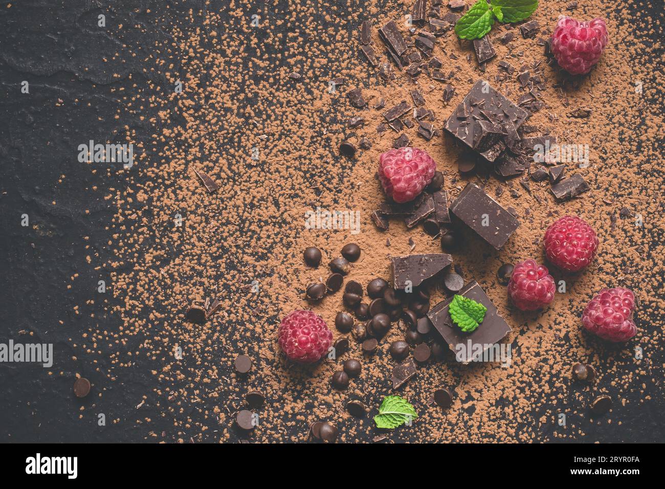 Pieces of dark chocolate, powder, drops and raspberries. Food dessert ...