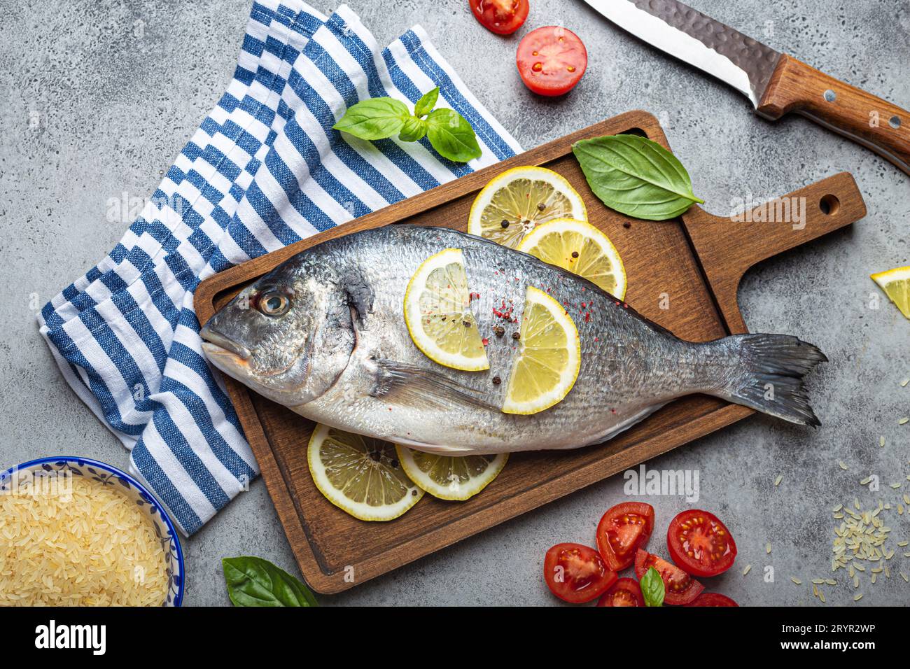 Raw fish dorado with ingredients lemon, fresh basil, cut cherry ...