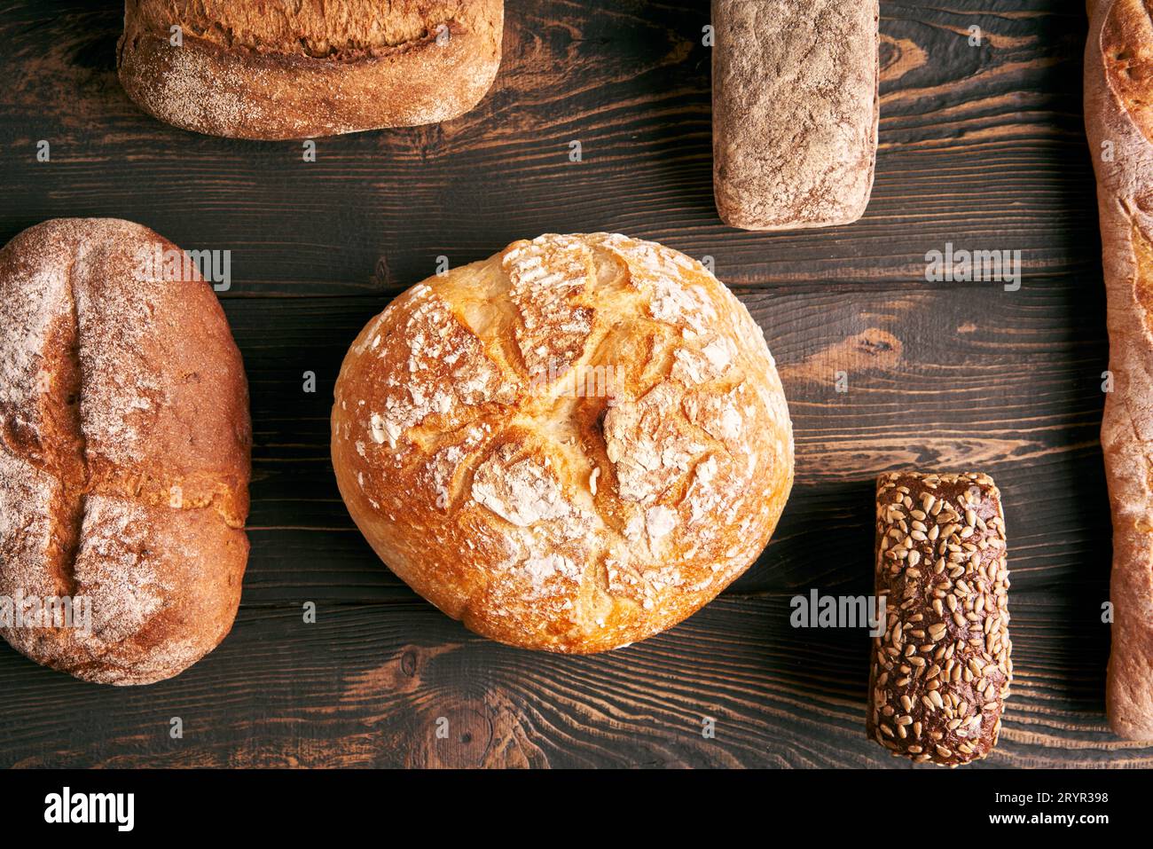 Different types of bread loaves on dark wooden background Stock Photo ...