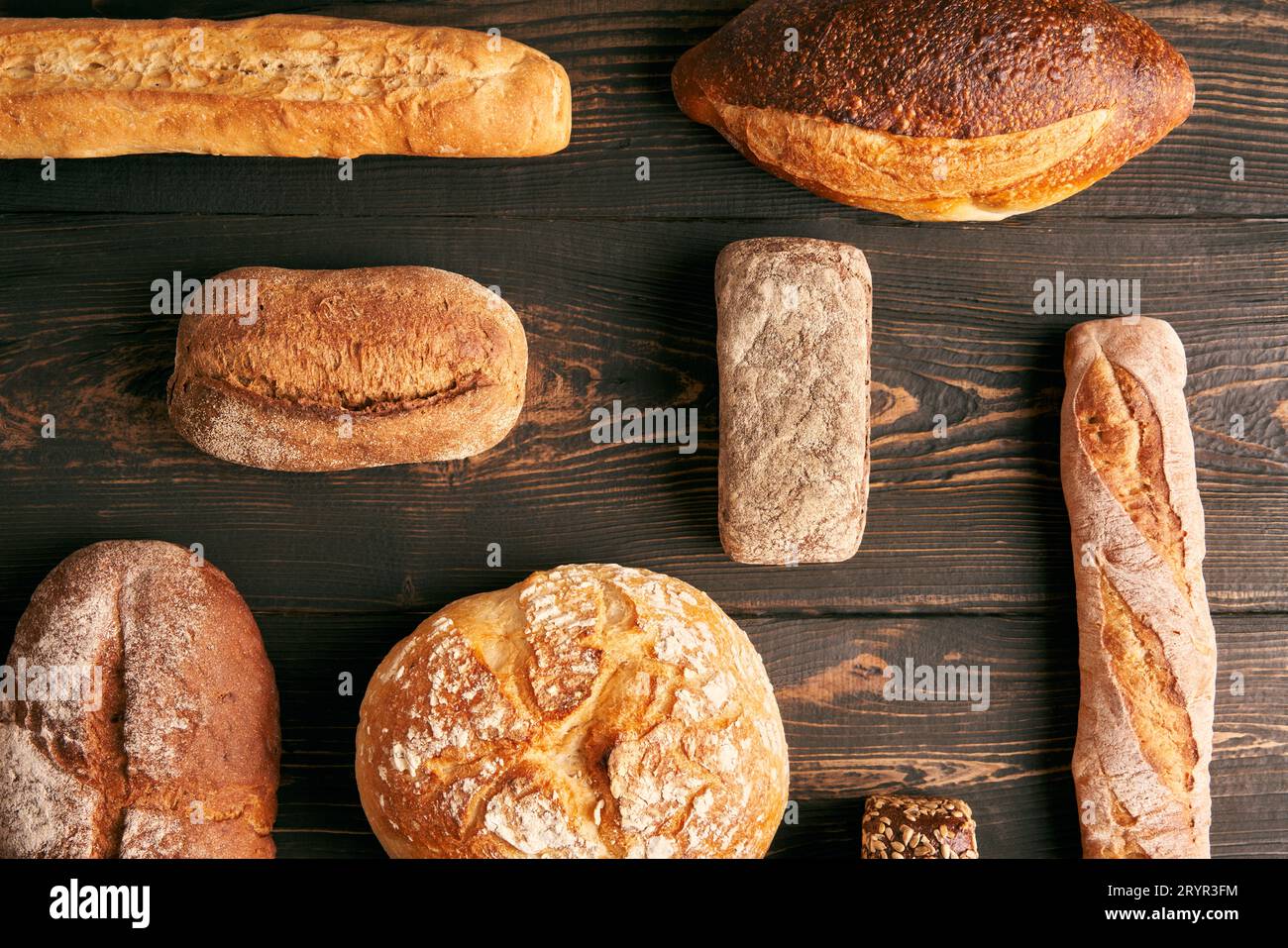 Different types of bread loaves on dark wooden background Stock Photo ...