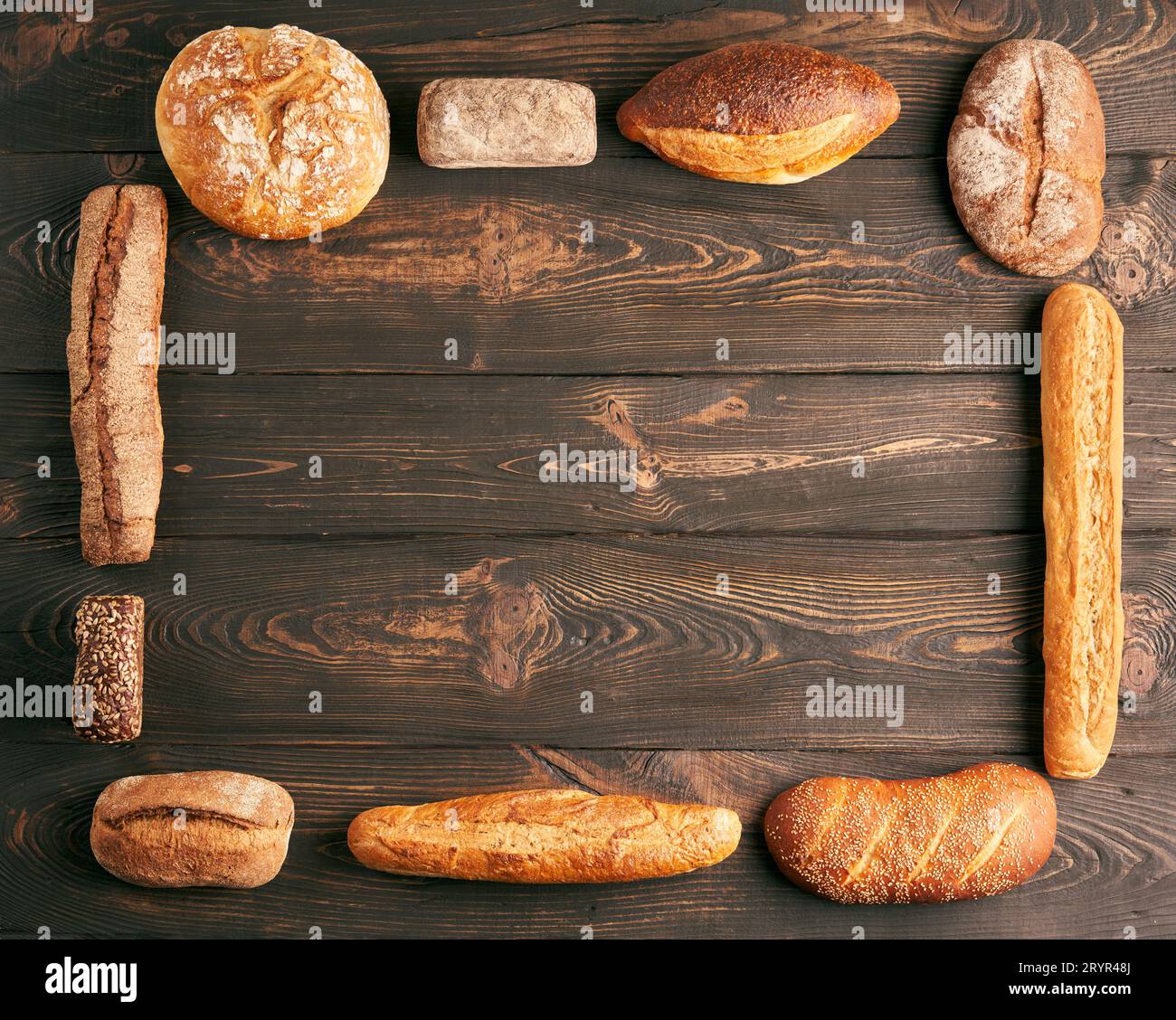 Frame of different types of bread loaves on wooden background with copy ...