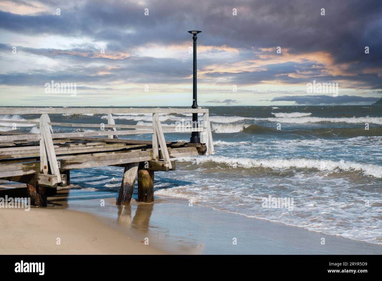 Storm sea waves empty wooden pier in dramatic blue sky background ...