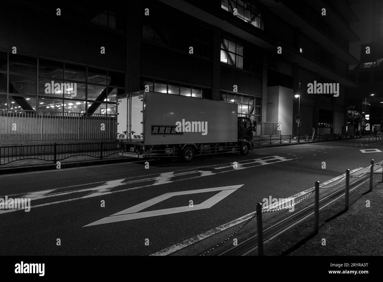 A grayscale shot of a large commercial truck traveling down a rural ...
