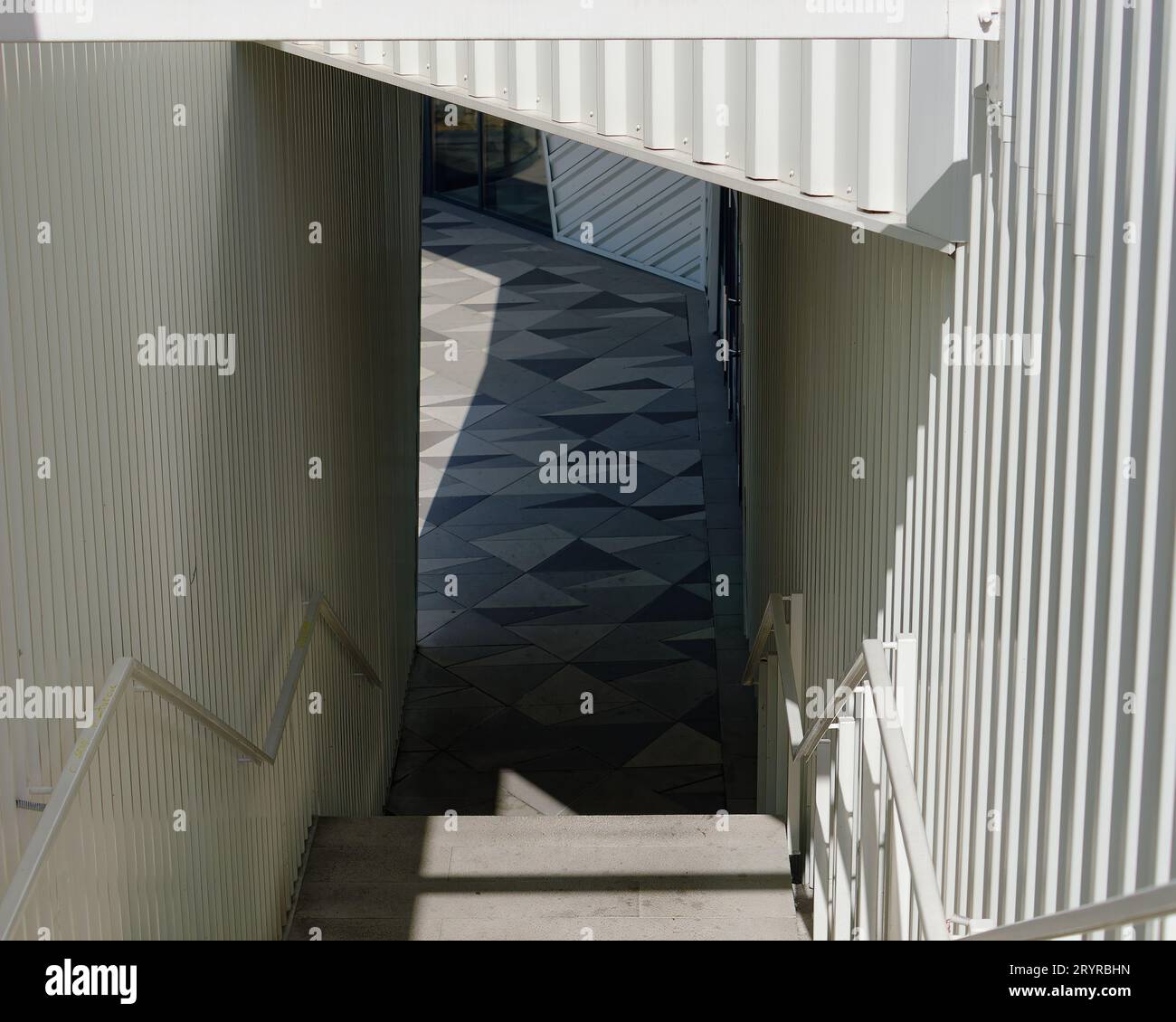 A modern urban landscape with two buildings connected by a sloping ramp ...