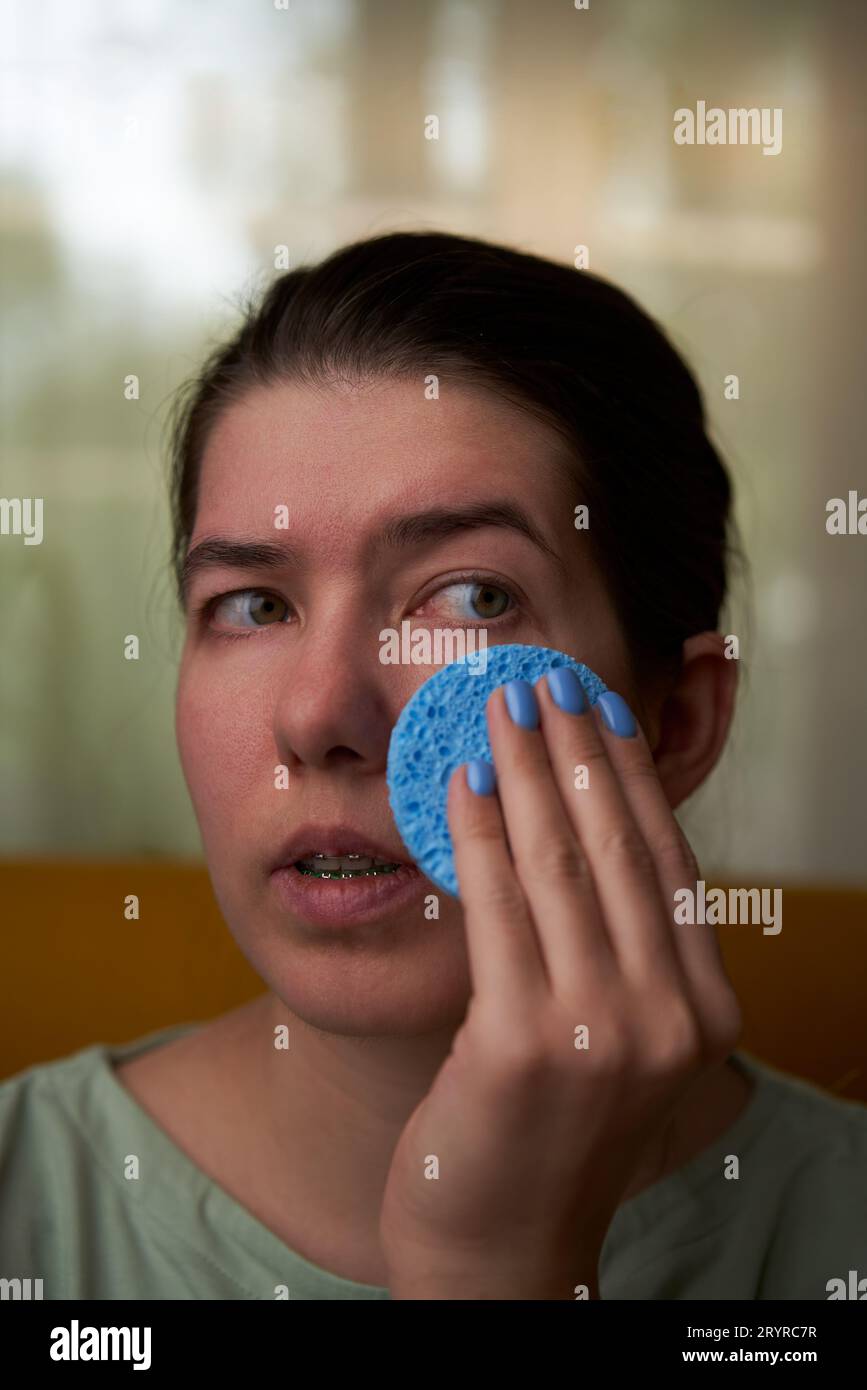 Woman is washing away face mask using mask remover sponge. Skin self ...