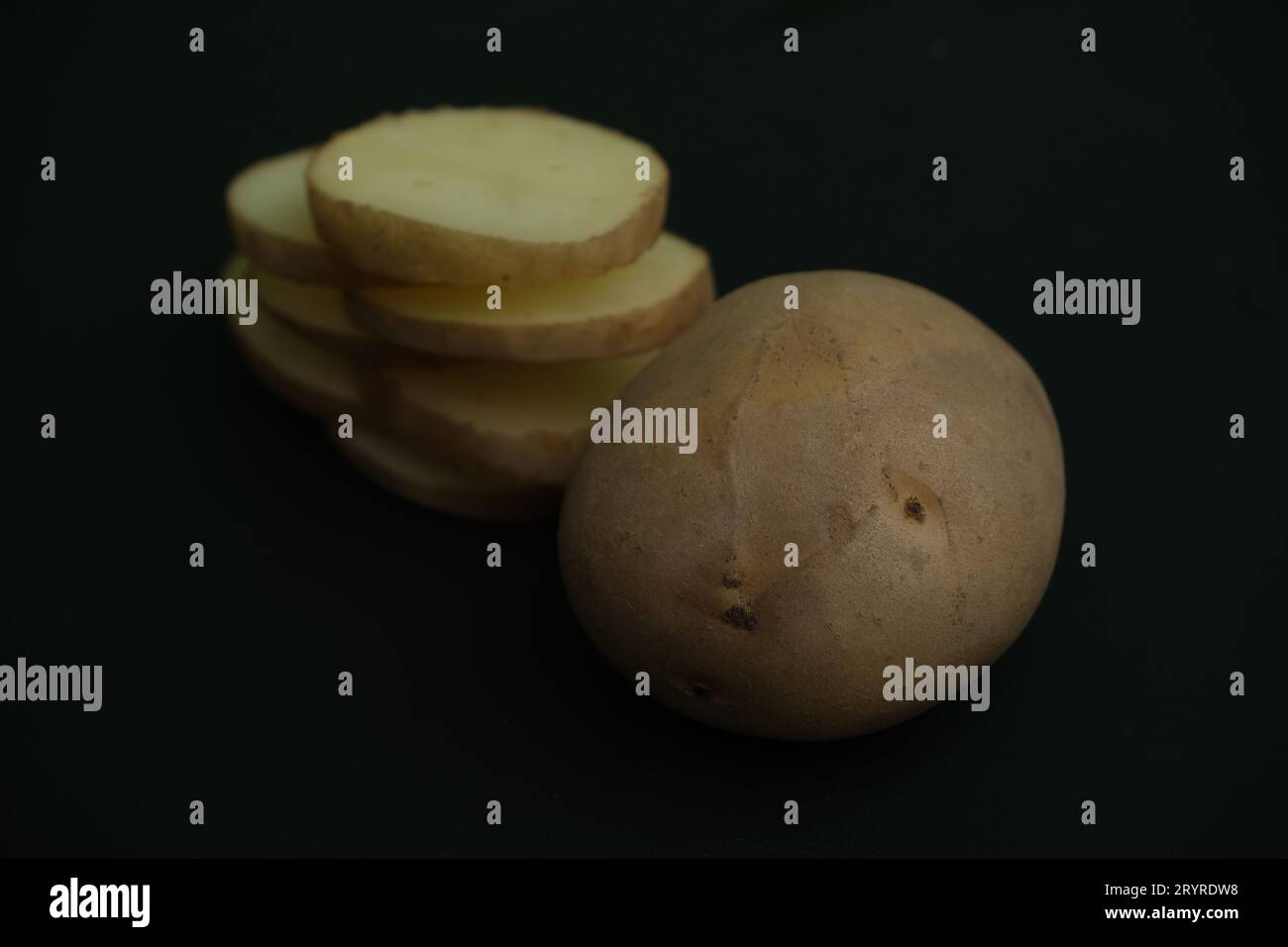 Potato slices and whole potato on black background , top view Stock ...