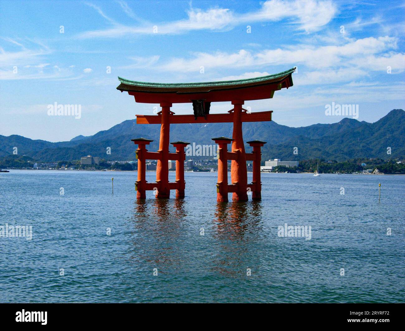 A traditional Japanese torii gate floating in a tranquil body of water ...