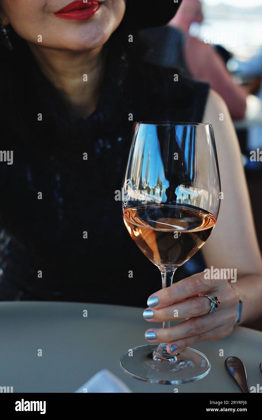 An elegant woman holding a glass of Rosé, with a reflection of the ...