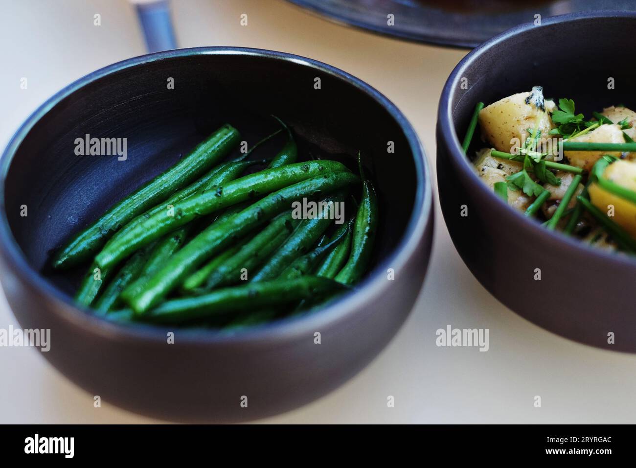 A dark ceramic bowl of green beans, & a bowl of small potatoes, lunch ...