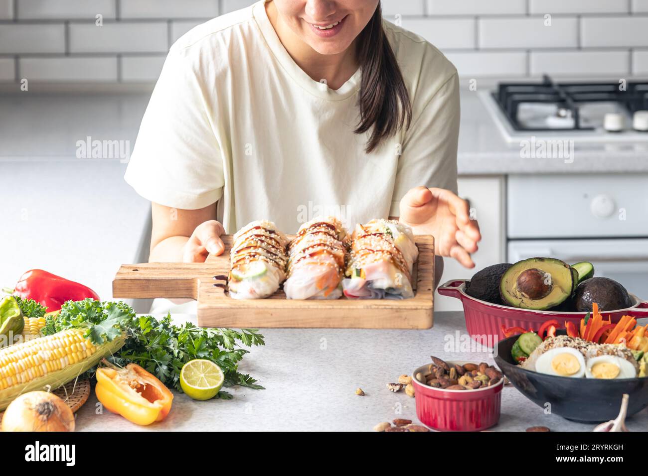 A young woman with spring rolls in rice paper in the kitchen Stock ...
