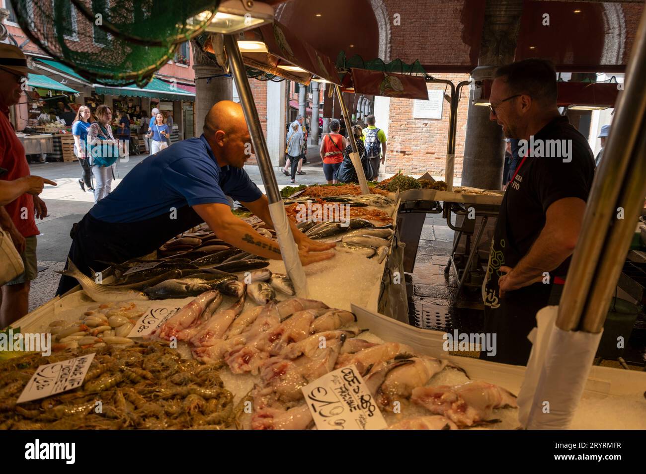A fishmonger packs down some ice to lay fresh fish on, at the Neo ...