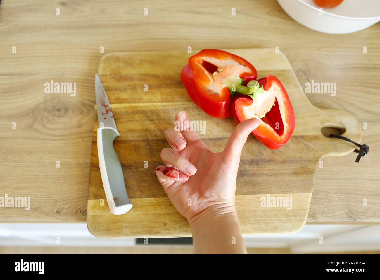 Woman cut her little finger with knife while cutting red pepper on the ...