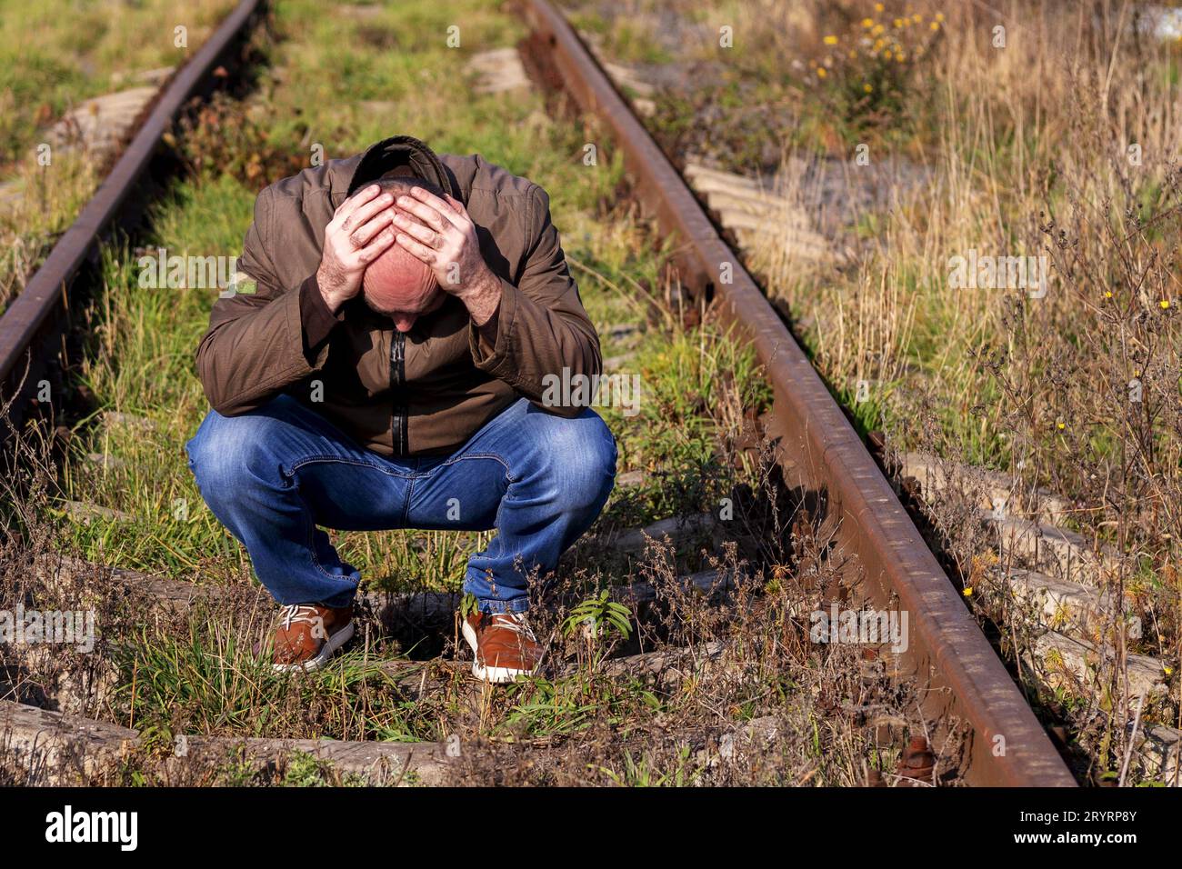 The thoughtful man sits on rails. The upset person in a stress. Concept ...