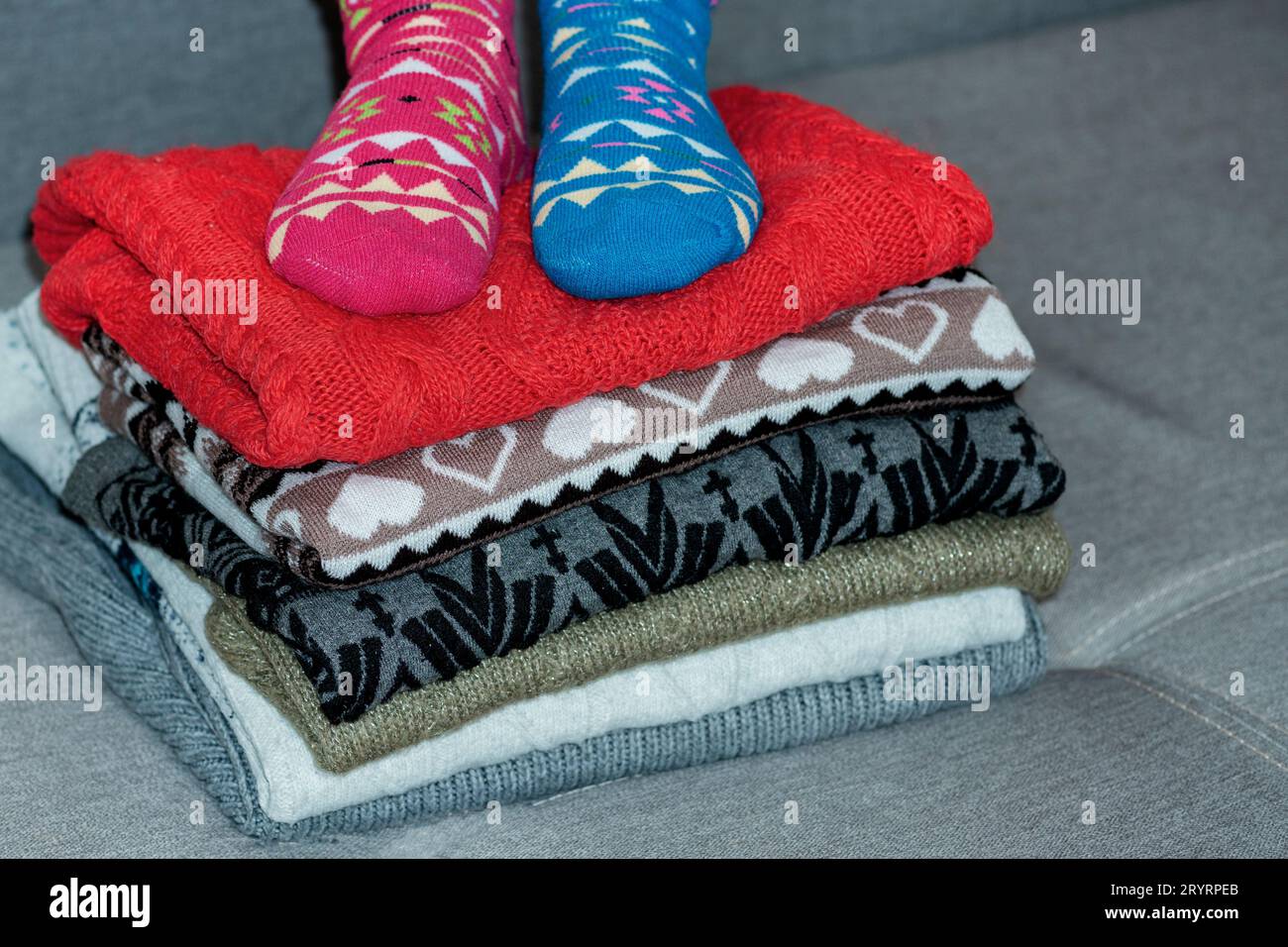 Stack of knitted colorful clothes . Women's legs in different beautiful ...
