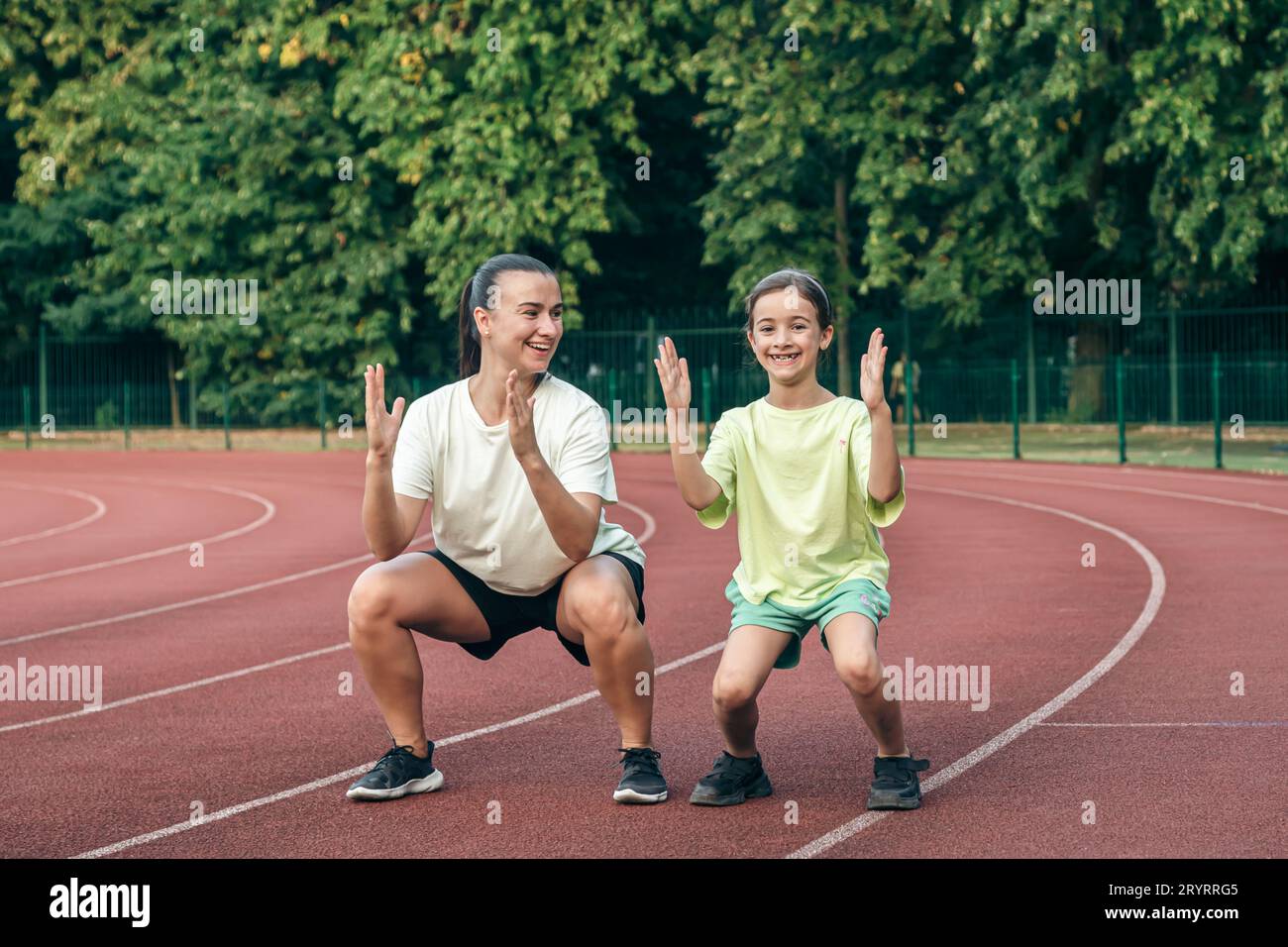 Mother and little daughter are doing exercise in the stadium Stock ...
