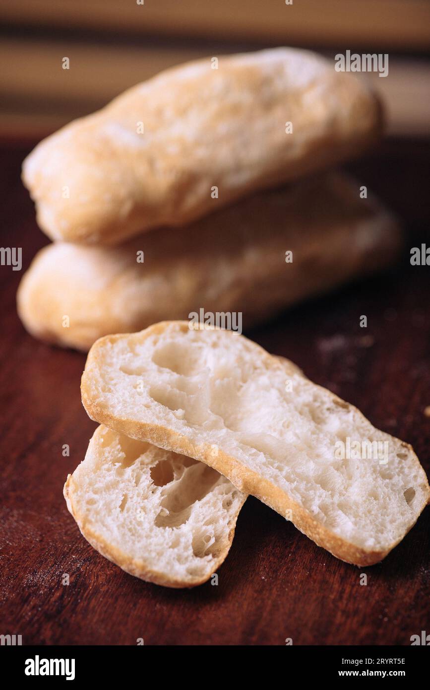 A vertical closeup shot of a halved bread roll near other rolls of ...