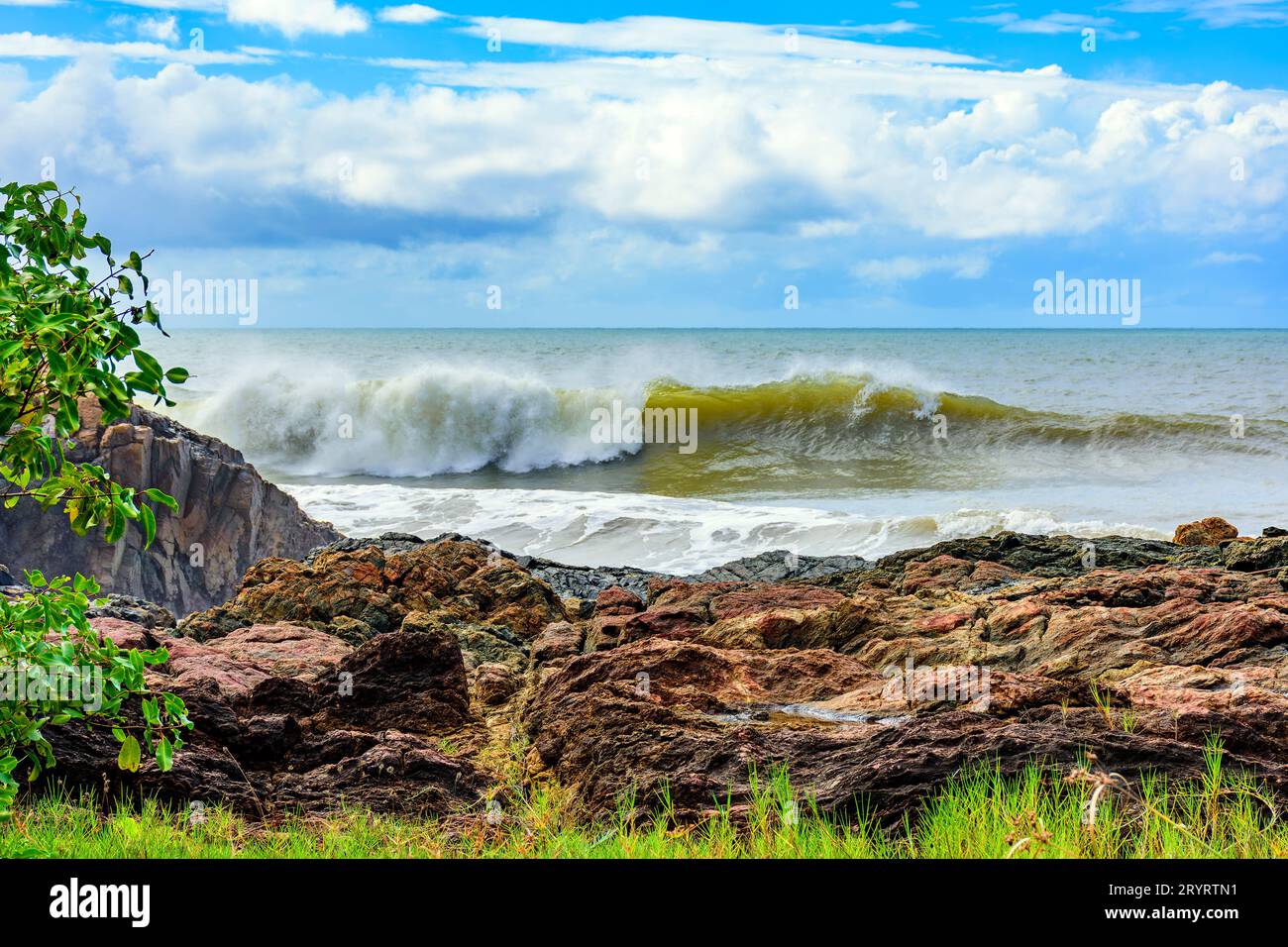 Wave breaking behind the rocks Stock Photo - Alamy
