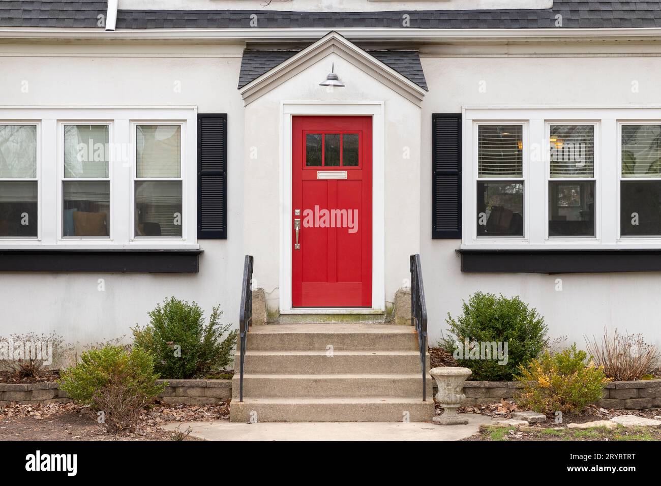 A red front door detail on a white home with concrete steps and iron ...