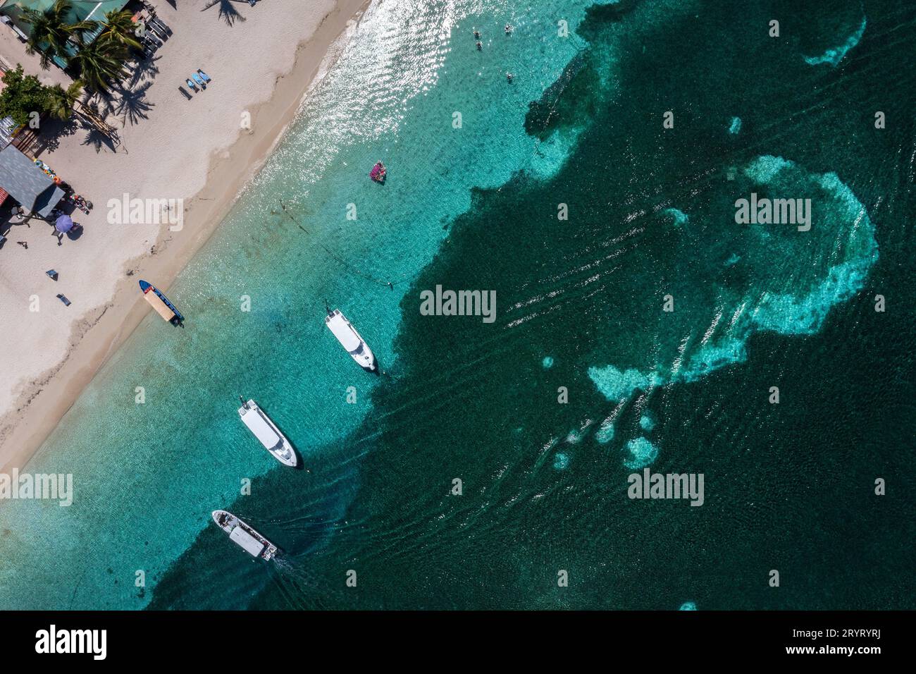 An aerial view of boats lined up on a sandy beach in Roatan Honduras ...