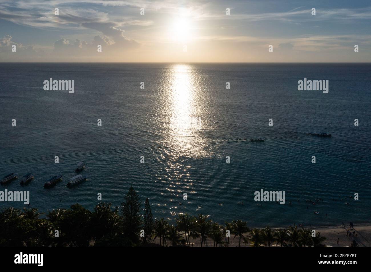 An aerial view of boats lined up on a sandy beach at sunset in Roatan ...