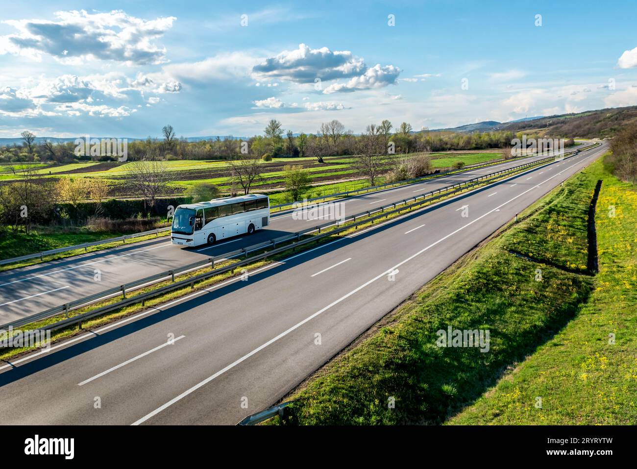 White Modern comfortable tourist bus driving through highway at bright ...