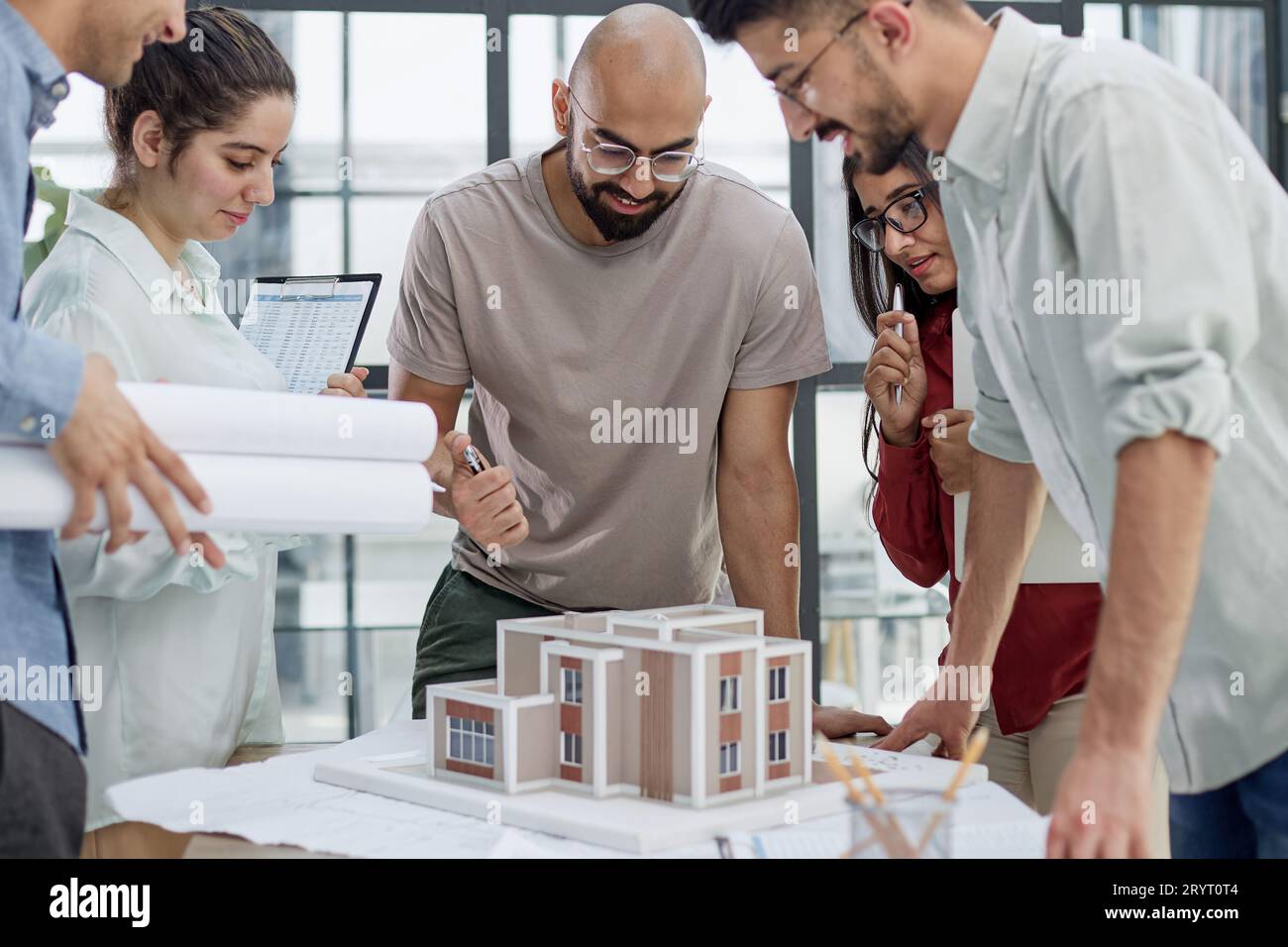 Miniature house on the table in the office with a team of architects ...