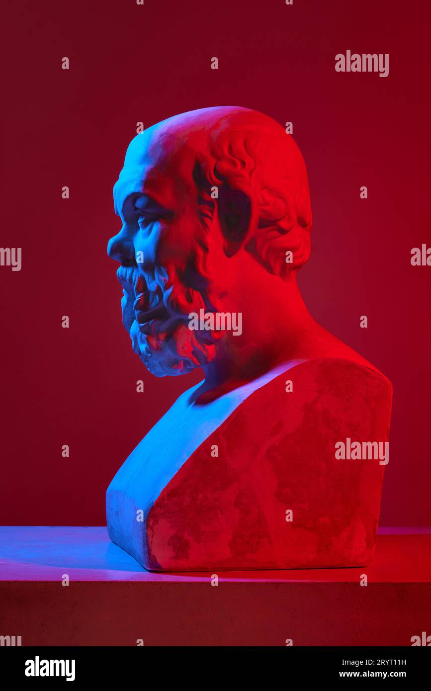 Antique statue bust of man against red studio background in neon lights ...