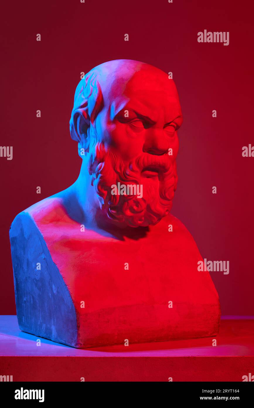 Antique statue bust of man against red studio background in neon lights ...