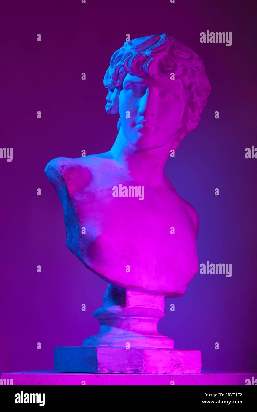 Greek art. Antique statue bust against purple studio background in neon ...
