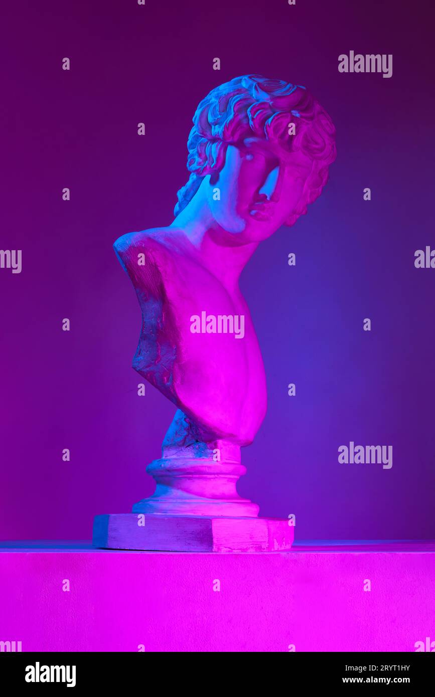 Greek art. Antique statue bust against purple studio background in neon ...