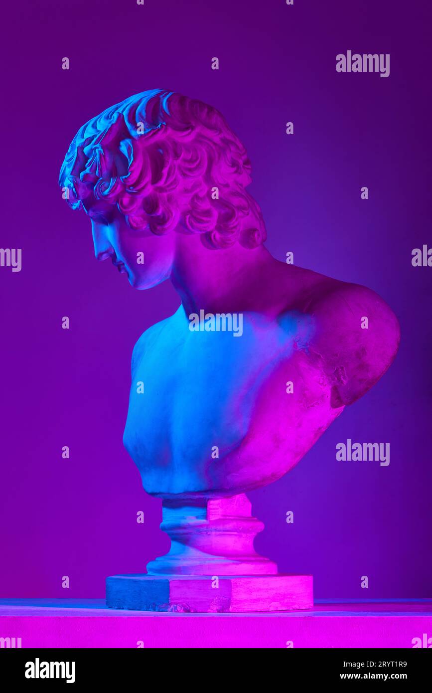 Greek art. Antique statue bust against purple studio background in neon ...