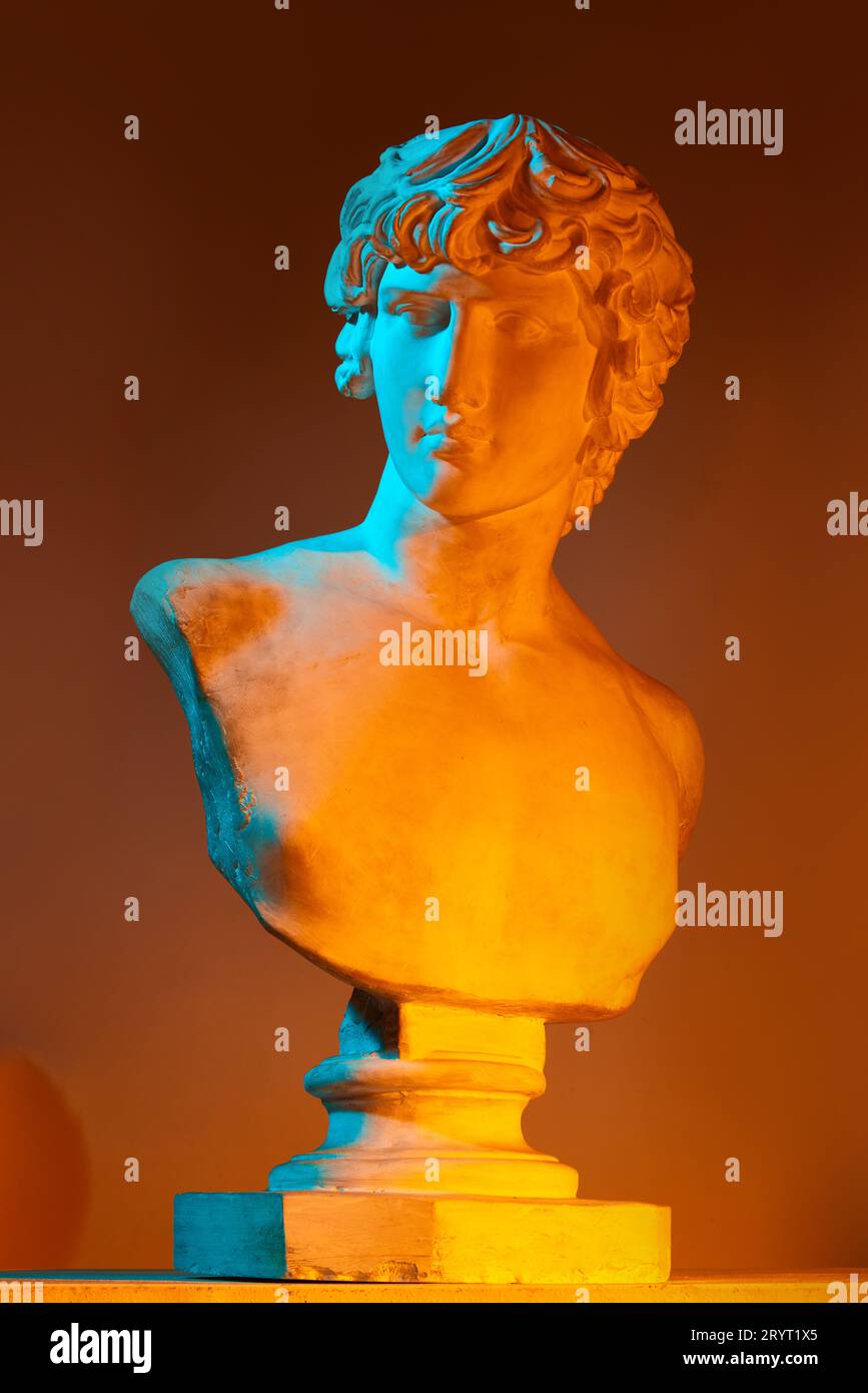 Antique statue bust against yellow studio background in neon lights ...