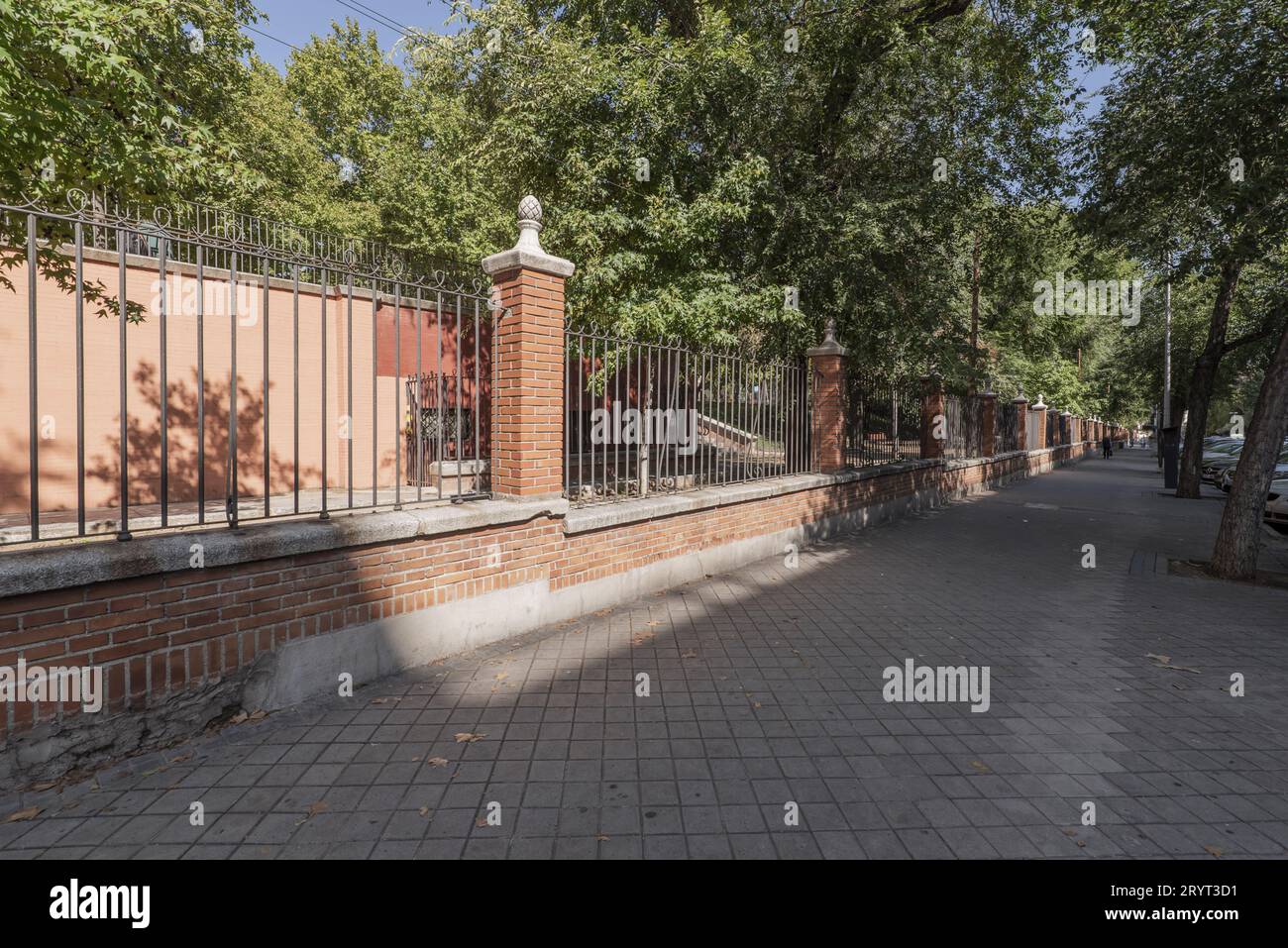 a long fence of brown brick posts and chairs and black metal railings ...