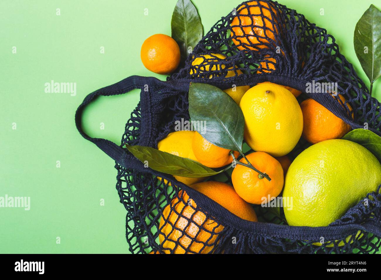 Black textile bag full of colorful citrus fruit. Healthy food and zero ...